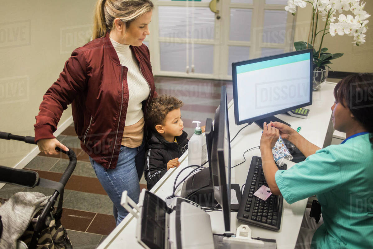 High angle view of pediatrician giving stickers to boy while mother ...