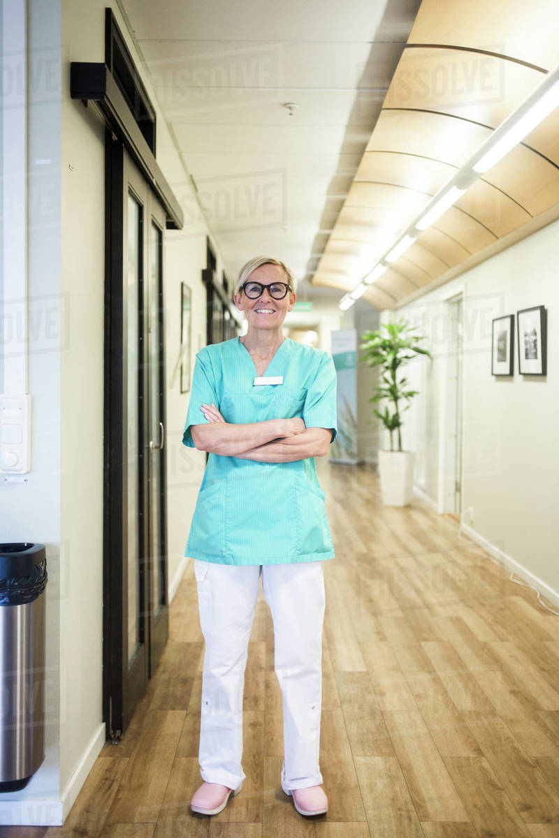 Full length portrait of mature female healthcare worker with arms ...