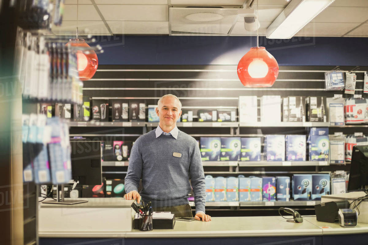 Portrait of smiling mature owner standing in electronics store ...