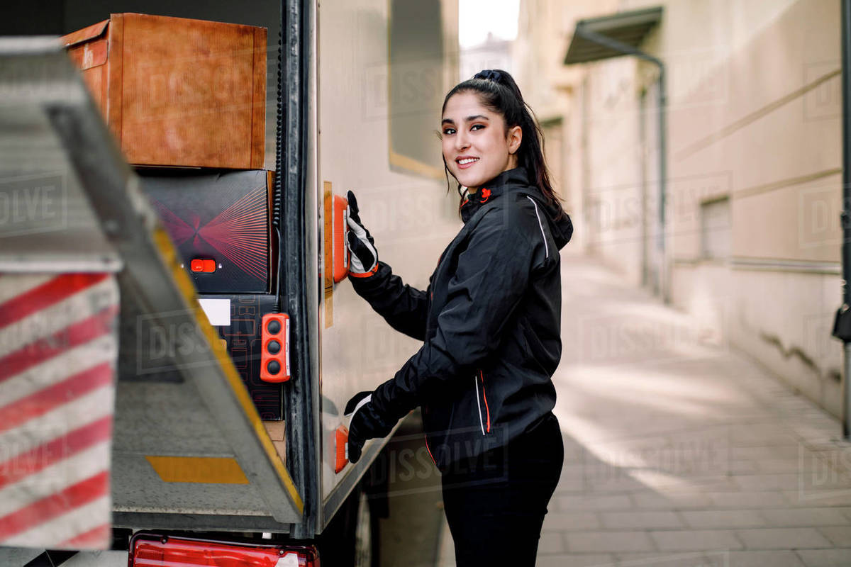 Side view portrait of young delivery woman with truck in city - Royalty ...