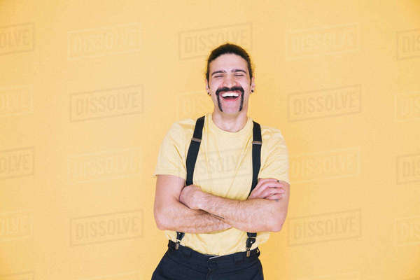 Happy man standing against yellow background - Stock Photo - Dissolve