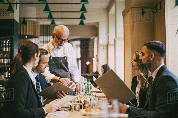 Waiter showing menu to business people in restaurant - Royalty-free ...