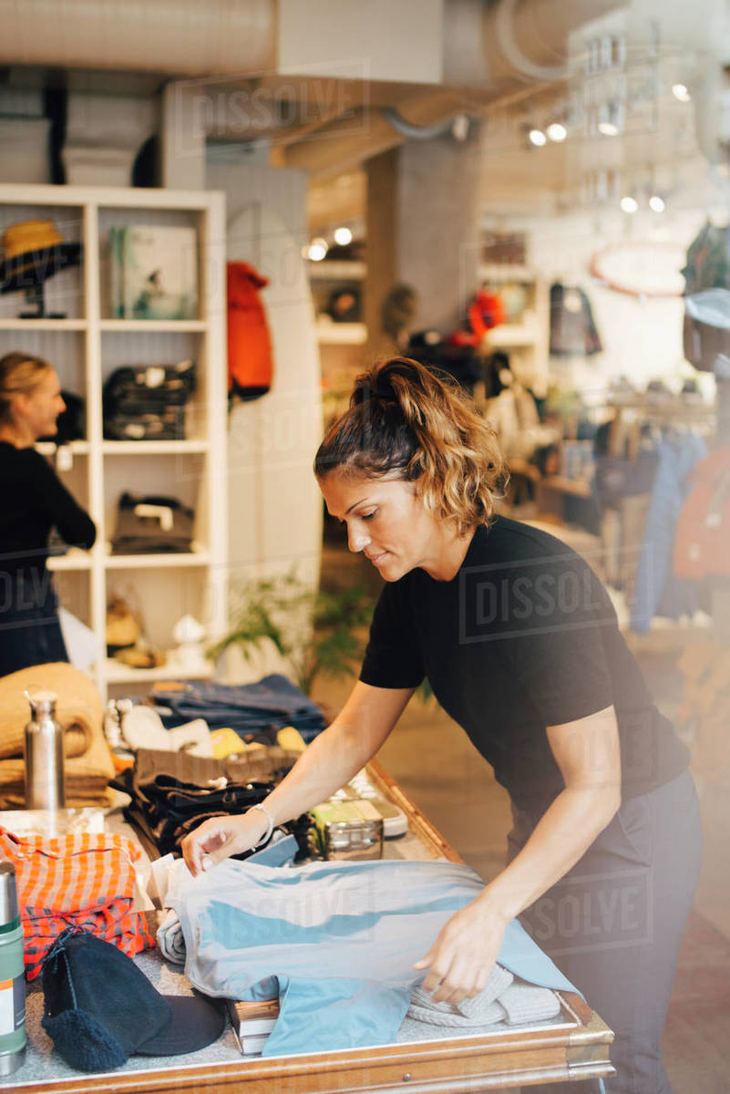 Female entrepreneur arranging clothes at store - Stock Photo - Dissolve