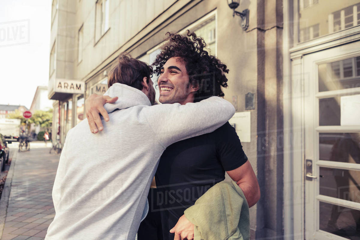 Cheerful male friends hugging each other outside cafe - Stock Photo ...