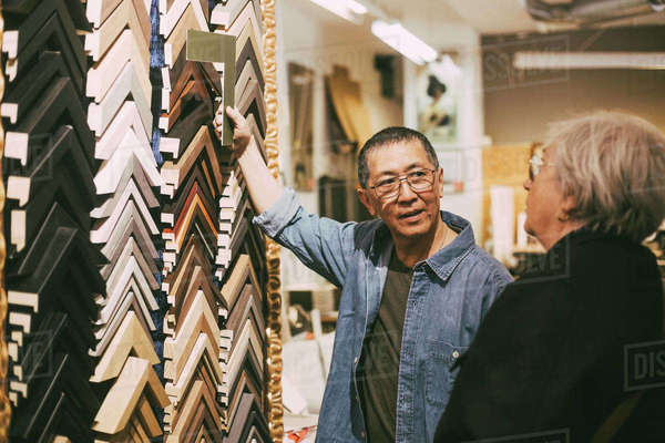 Craftsman showing frames to female customer at workshop - Royalty-free ...