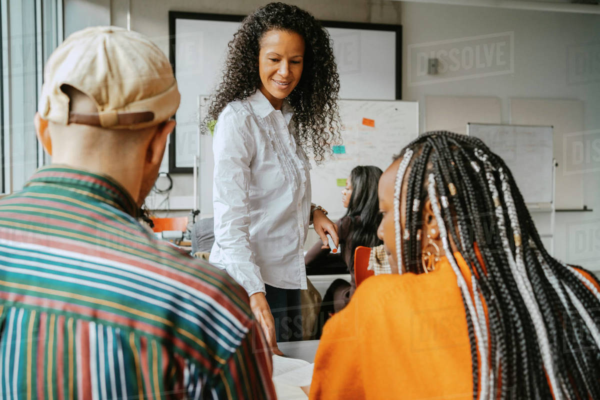 Female professor teaching students in classroom at community college ...