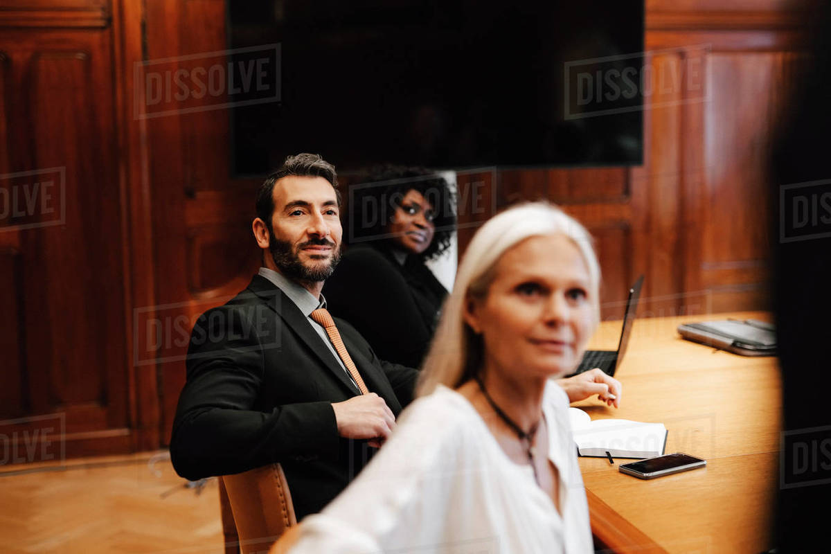 Multiracial colleagues sitting at conference table in board room during ...