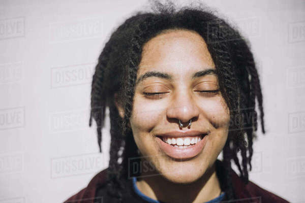 Happy young genderqueer person standing with eyes closed during sunny ...