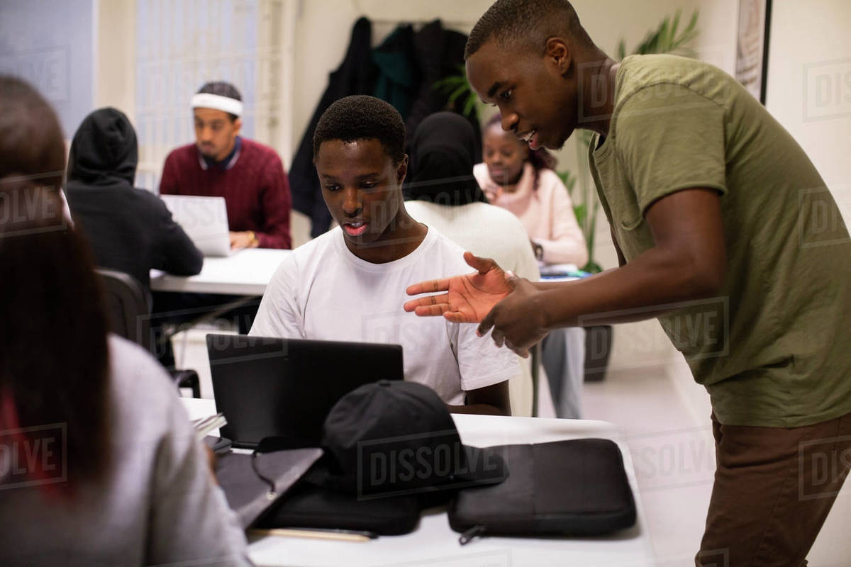 Teacher instructing student using laptop in classroom - Royalty-free ...