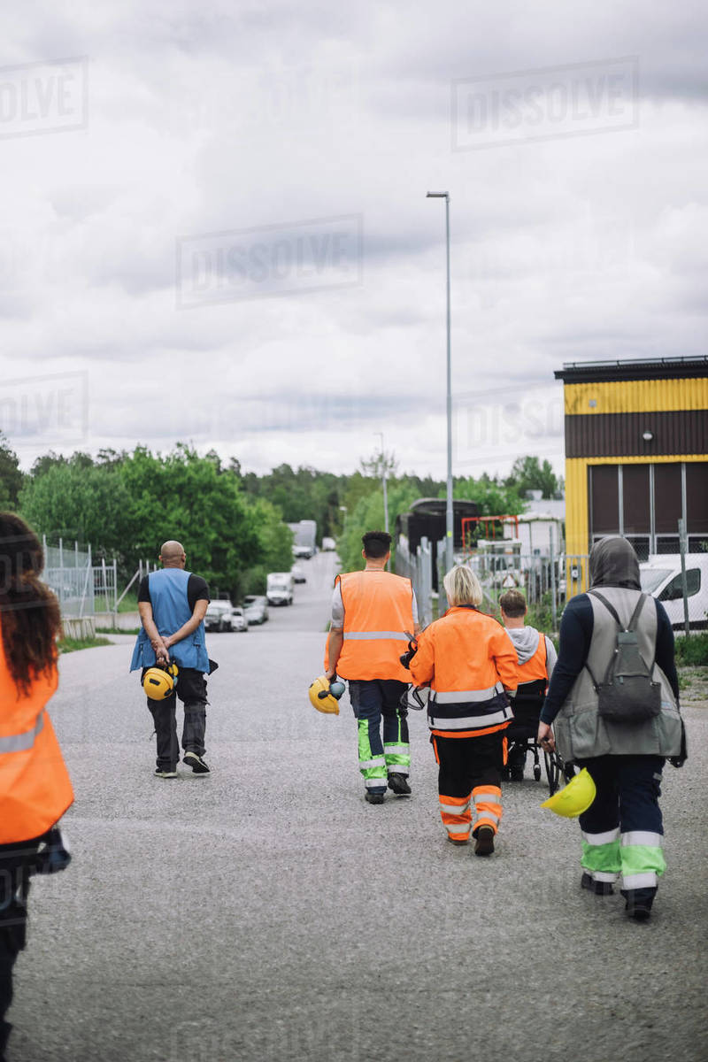 Rear view of male and female construction workers walking together on ...