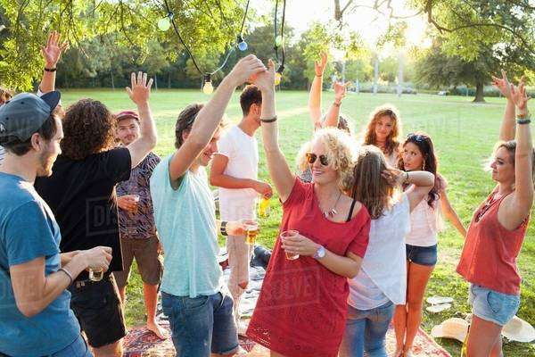 Crowd of adult friends dancing at party in park at sunset - Royalty ...