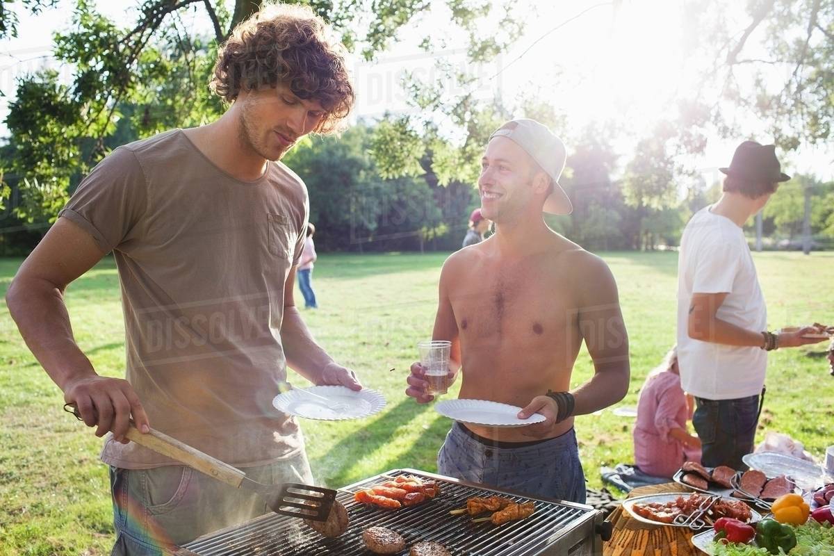 Young men barbecuing at sunset park party - Royalty-free Stock Photo ...