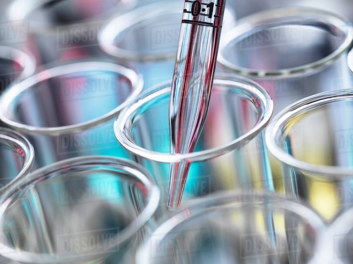 High angle cropped view of graduated pipette pipetting liquid into test ...