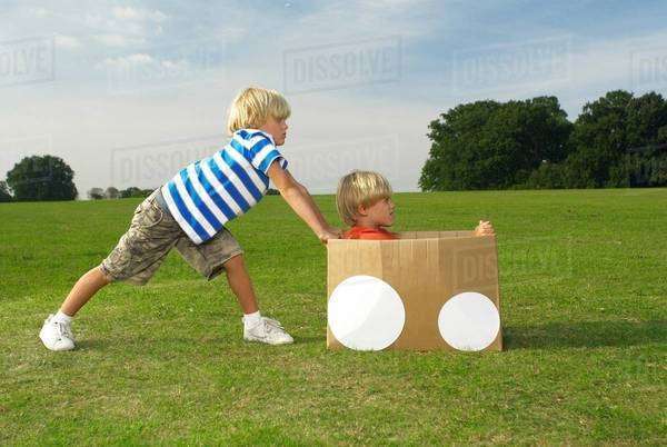 Boys pushing another boy in box - Royalty-free Stock Photo | Dissolve