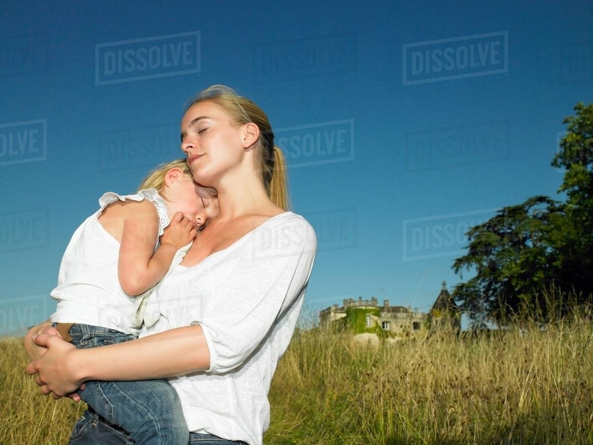 Mother carrying her sleeping daughter - Stock Photo - Dissolve