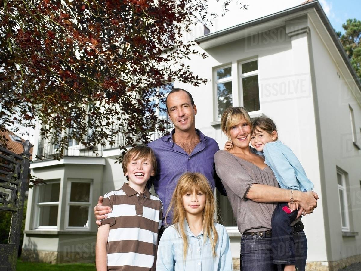 Family standing in front of their house - Stock Photo - Dissolve