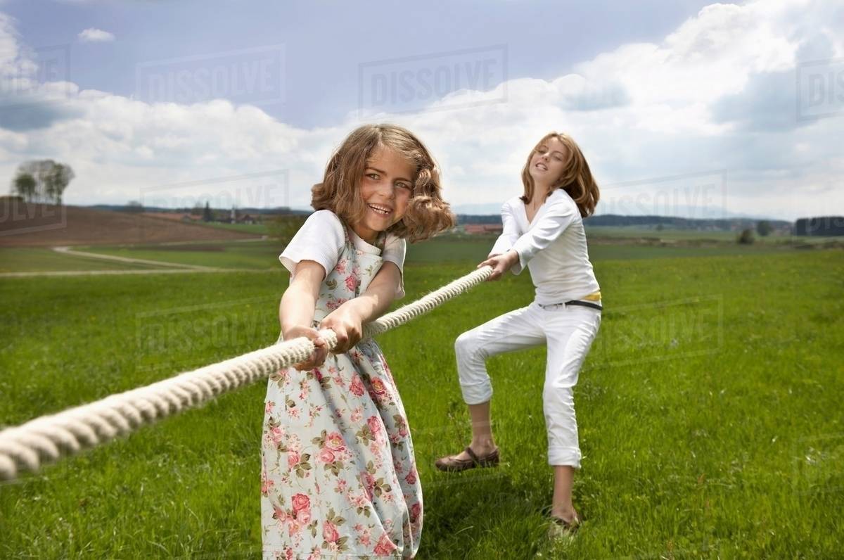 Children pulling a rope in countryside - Stock Photo - Dissolve