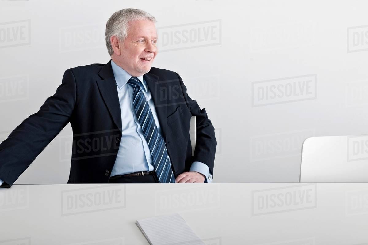 Man sitting, smiling at desk - Royalty-free Stock Photo | Dissolve