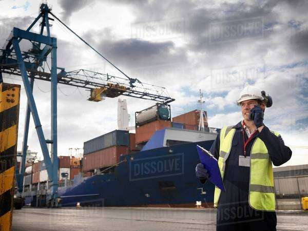 Port Worker In Front Of Loaded Ship - Stock Photo - Dissolve