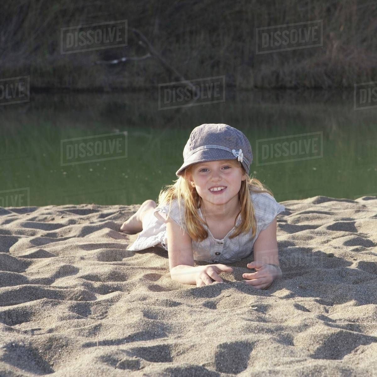 Young girl laying on sand by river - Royalty-free Stock Photo | Dissolve
