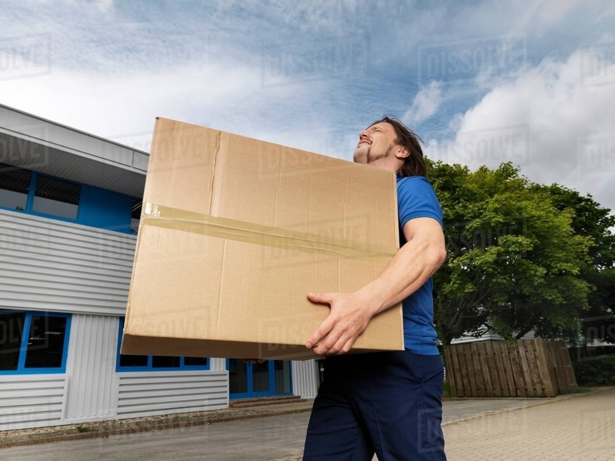 Man carrying heavy box - Royalty-free Stock Photo | Dissolve