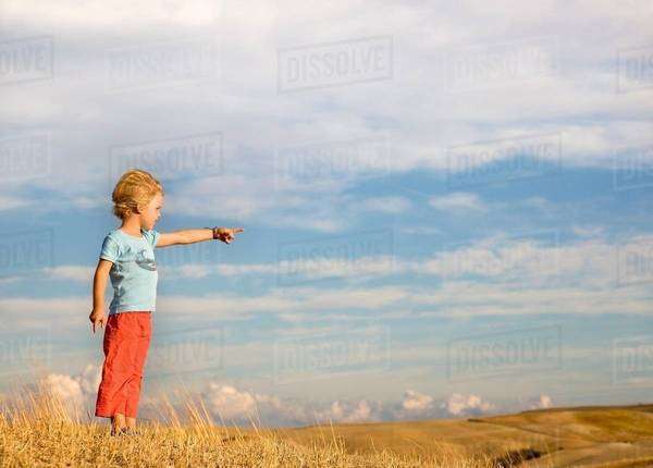 Boy pointing into distance - Stock Photo - Dissolve