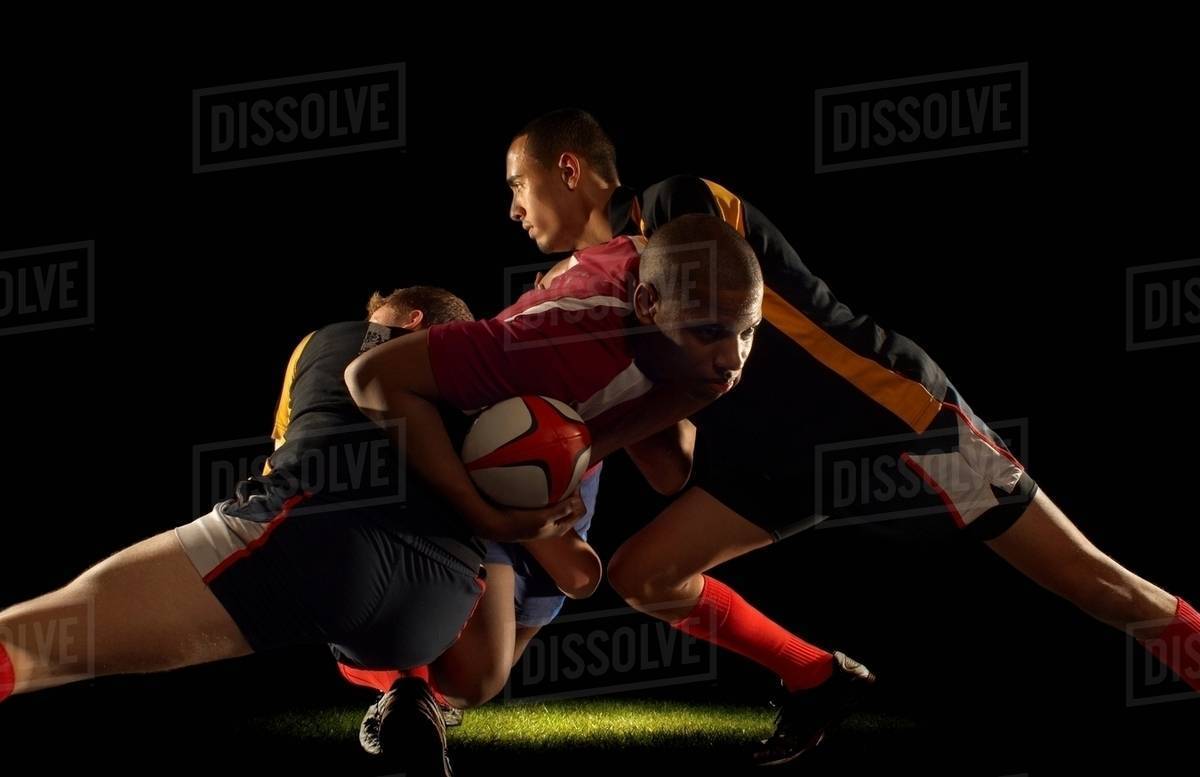 Rugby player tackled by two opponents - Stock Photo - Dissolve