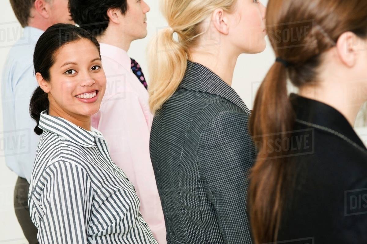 Women in line of people smiles to camera - Stock Photo - Dissolve