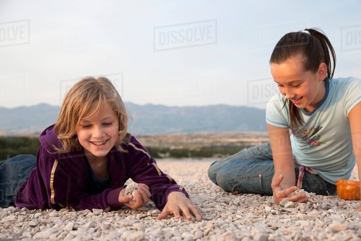 Girls collecting stones at the beach - Royalty-free Stock Photo | Dissolve