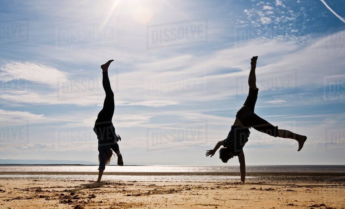 Two people cartwheeling on beach - Royalty-free Stock Photo | Dissolve