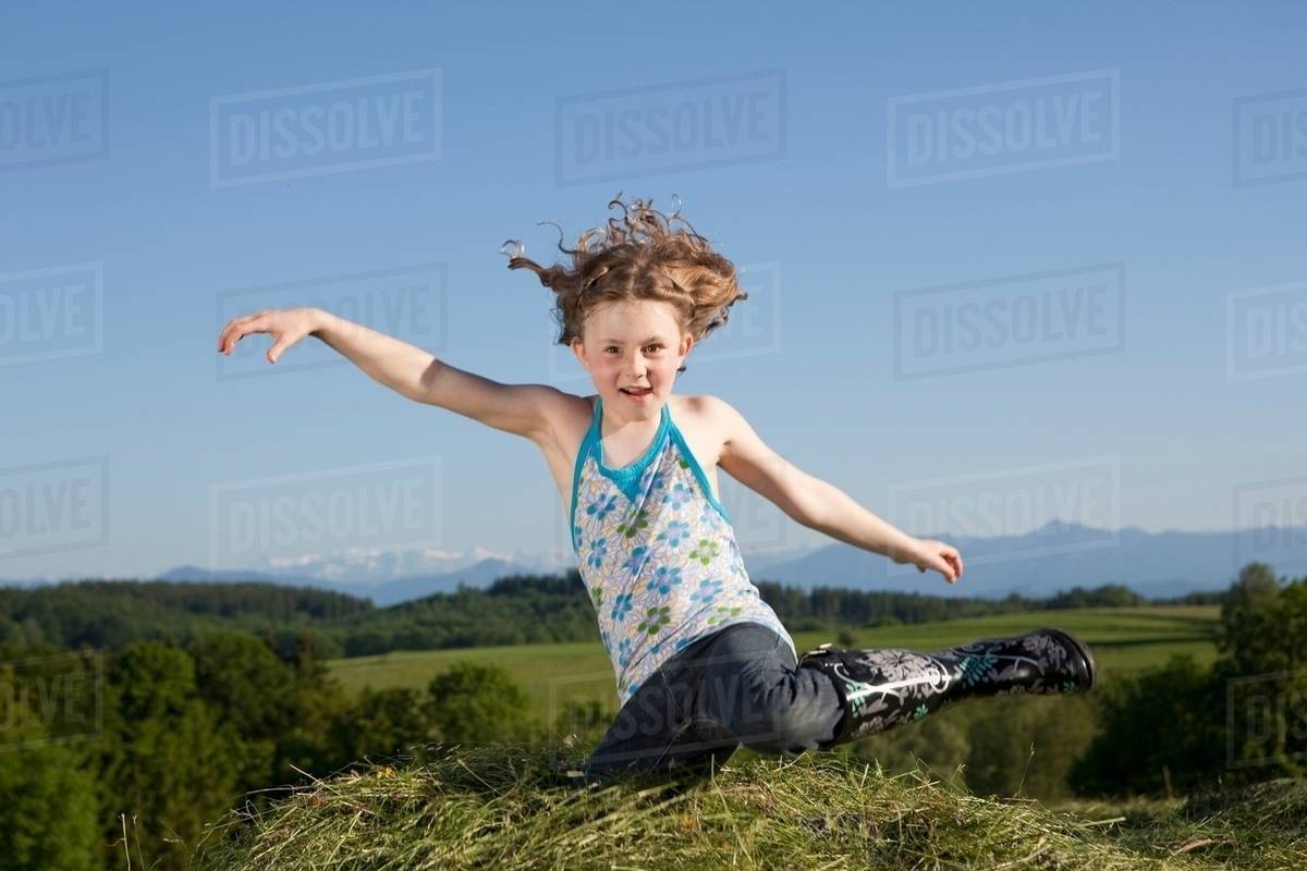 Girl jumping in grass - Stock Photo - Dissolve