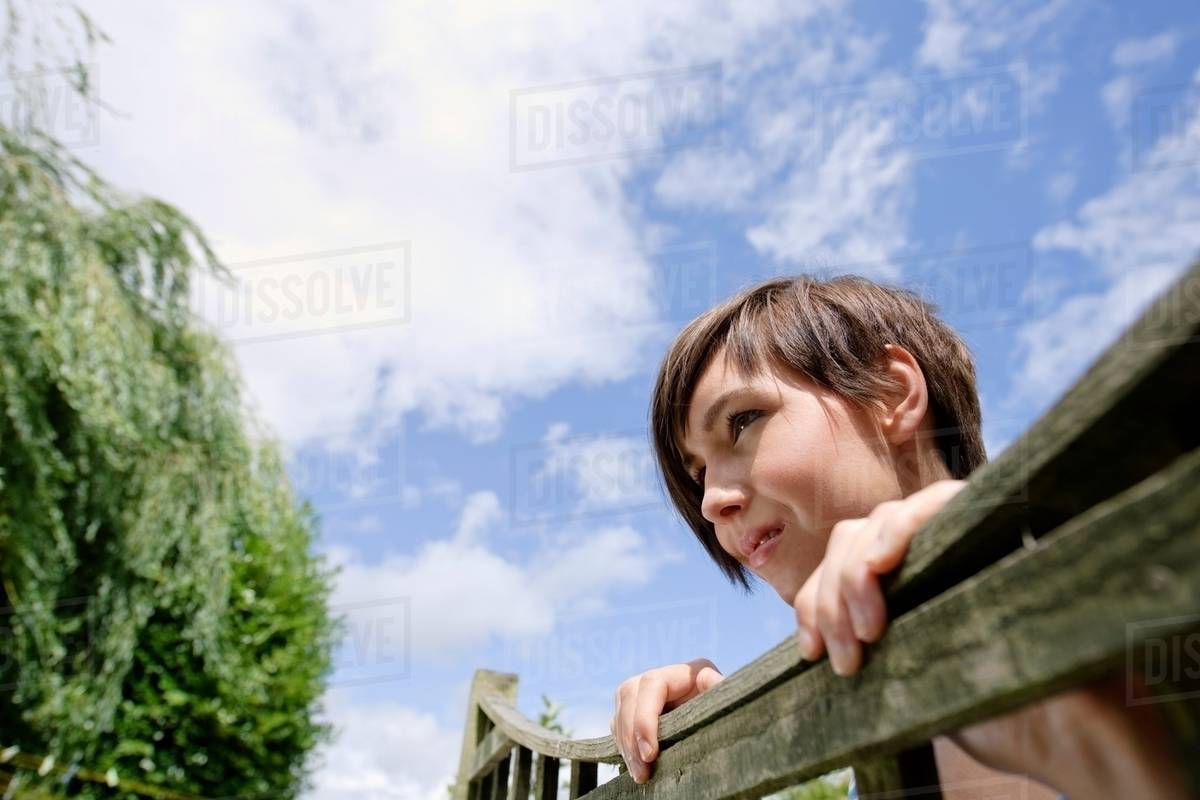 Woman looking over fence - Stock Photo - Dissolve