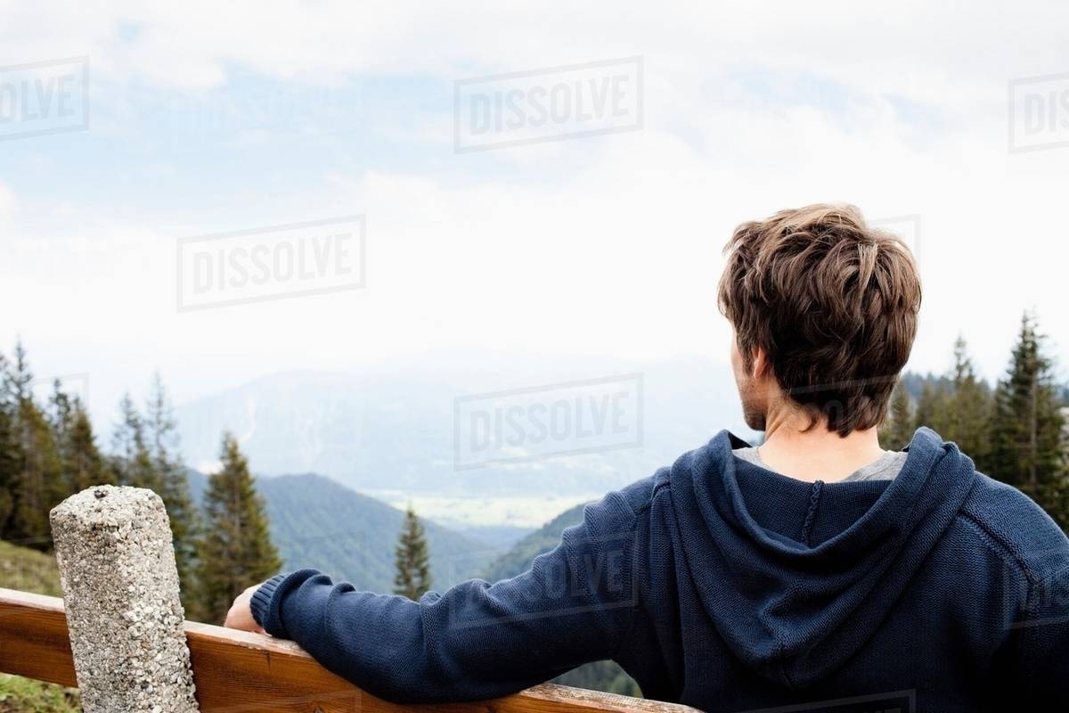 Man sitting on bench watching landscape - Stock Photo - Dissolve