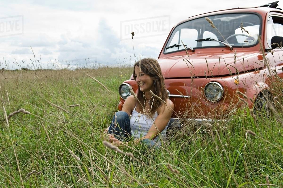 Relaxed female by car in countryside - Stock Photo - Dissolve