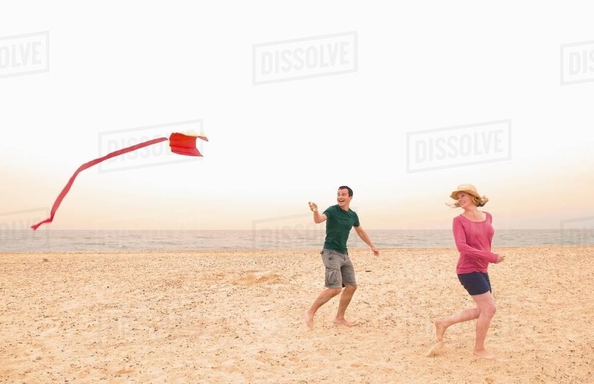 Happy couple fly kite on beach - Royalty-free Stock Photo | Dissolve