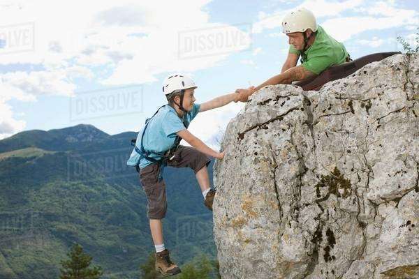 Man helping boy to get to the top - Royalty-free Stock Photo | Dissolve