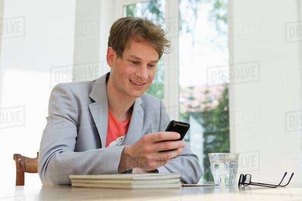 Young man checking his phone - Royalty-free Stock Photo | Dissolve