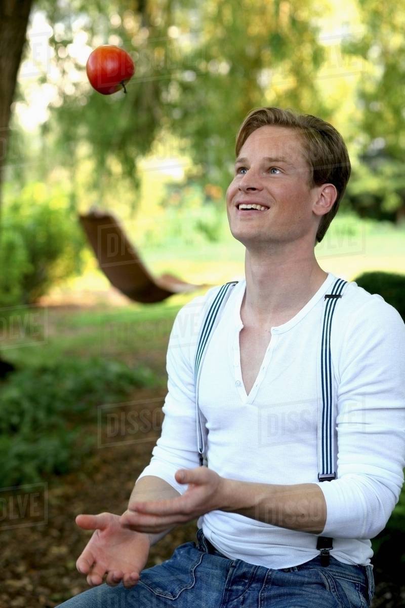 Young man throwing an apple - Royalty-free Stock Photo | Dissolve