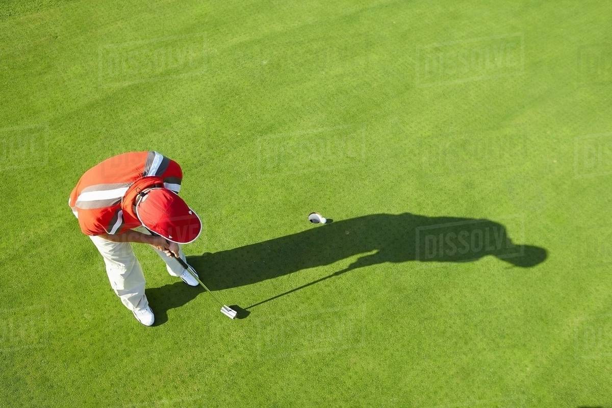 High view of golfer and shadow putting - Stock Photo - Dissolve