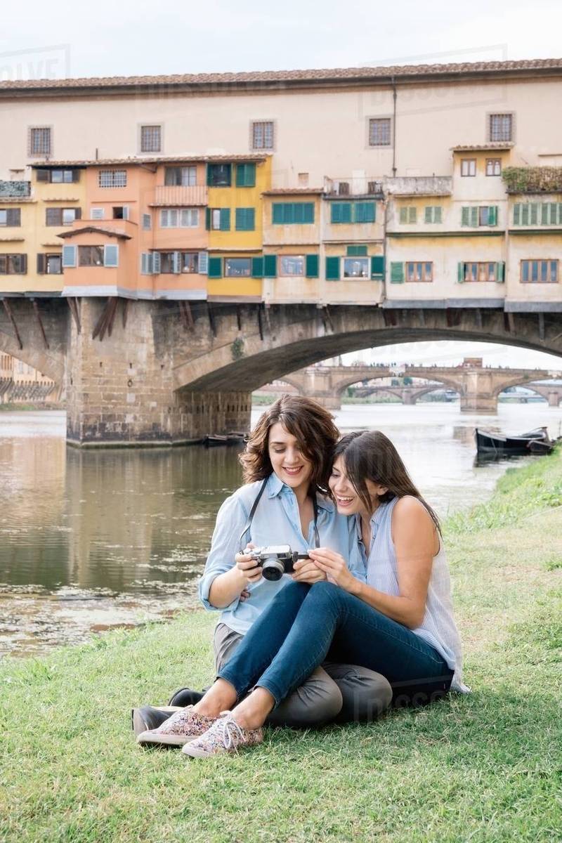 Lesbian couple sitting together looking at digital camera in front of ...