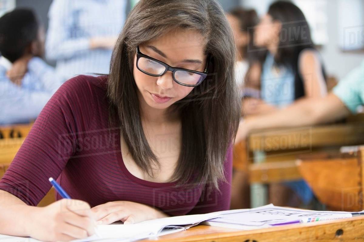 Female student, sitting at desk in classroom, writing - Royalty-free ...