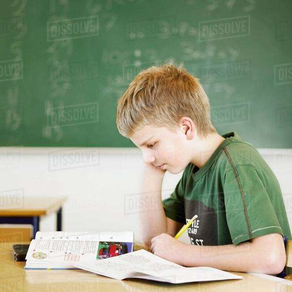 Boy studying at desk in classroom - Royalty-free Stock Photo | Dissolve