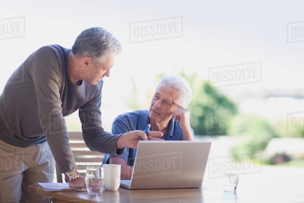 Older men using laptop together - Royalty-free Stock Photo | Dissolve