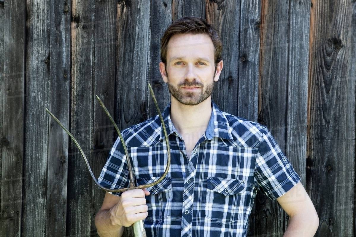 Man holding rake outdoors - Royalty-free Stock Photo | Dissolve