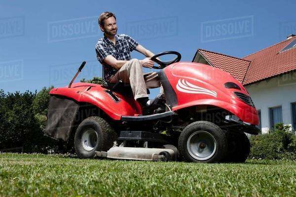 Man riding lawn mower in backyard - Royalty-free Stock Photo | Dissolve