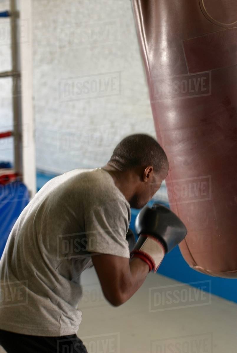 Boxer using punching bag in gym - Royalty-free Stock Photo | Dissolve