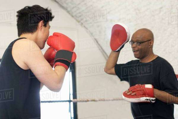 Boxer training with coach in gym - Royalty-free Stock Photo | Dissolve