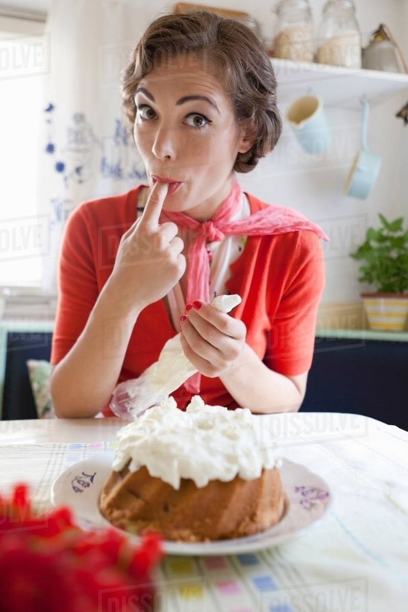 Woman icing a cake in kitchen - Stock Photo - Dissolve