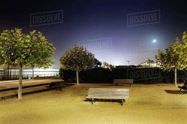 Empty park bench by river at night - Stock Photo - Dissolve