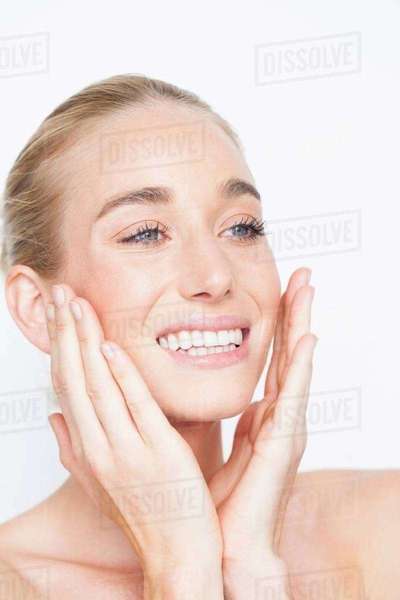 Bare shouldered woman with hands to face looking away smiling - Royalty ...